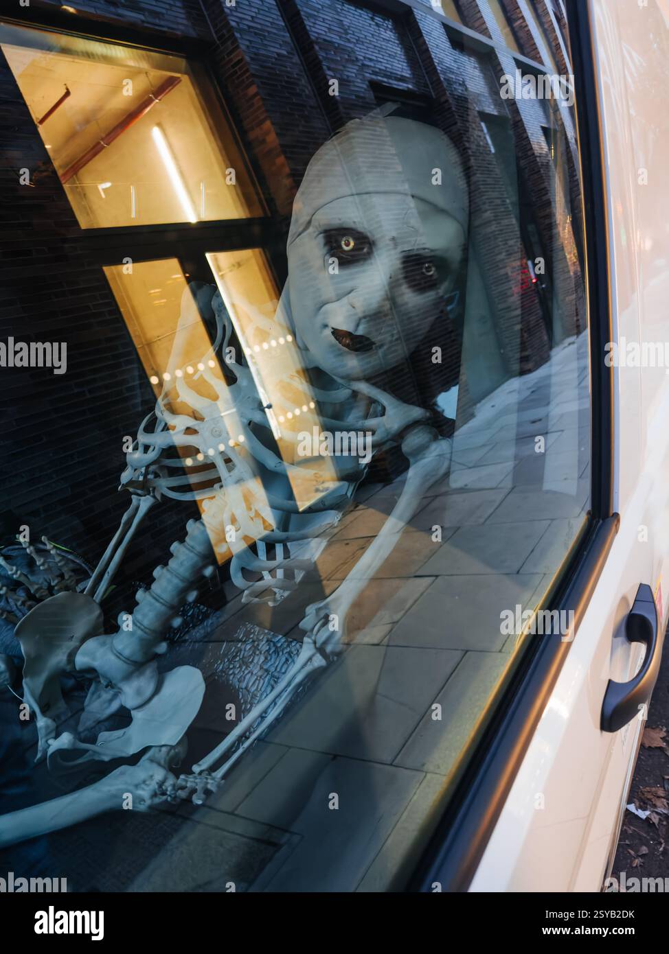 A haunting skeleton figure peers through a city window, its eerie ...