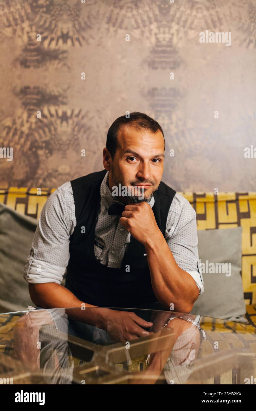 A professional bartender poses confidently in an upscale cocktail bar ...