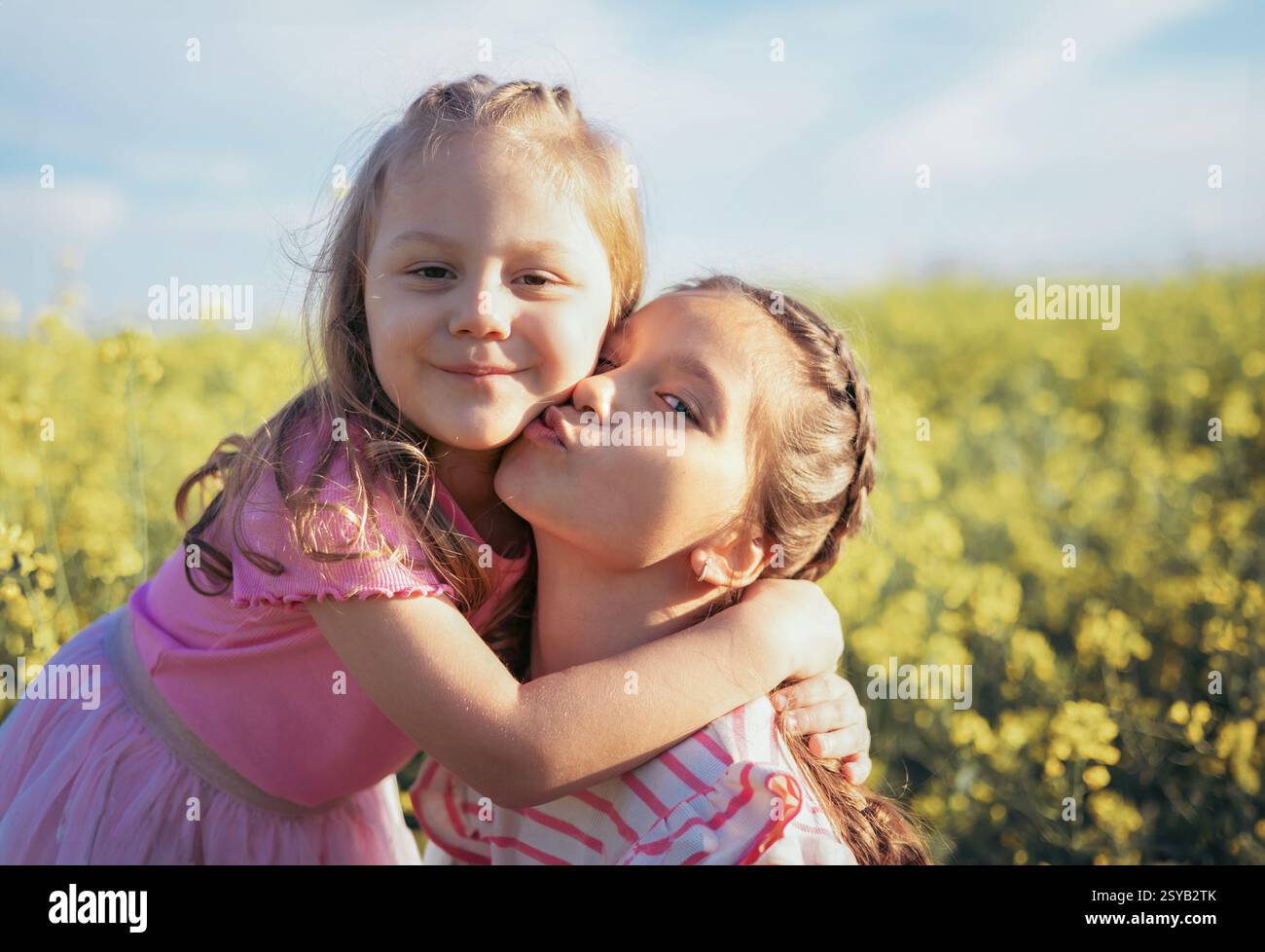 A sweet moment between two sisters as one gives the other a kiss on the ...