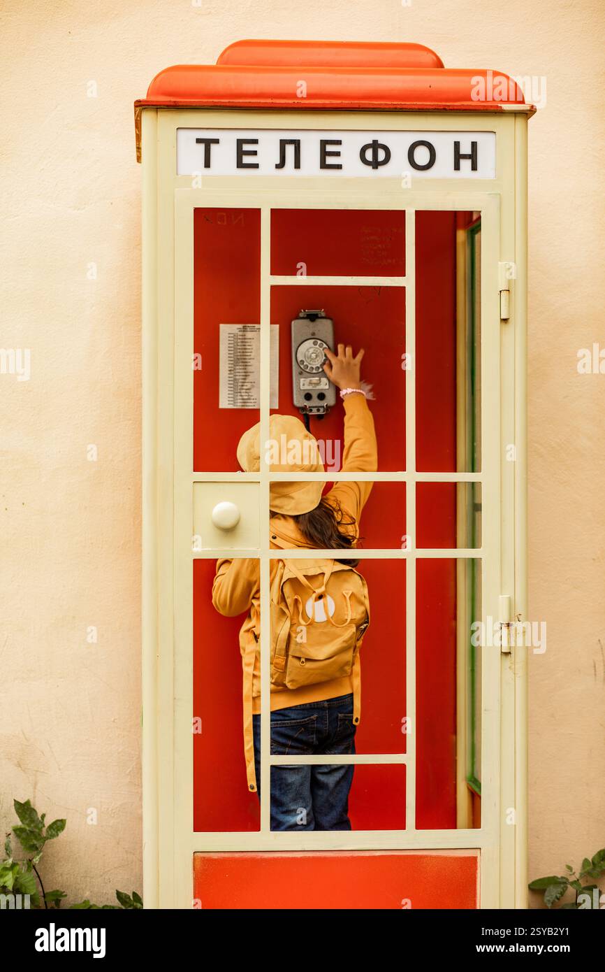 Unrecognizable preteen girl is seen reaching up to a vintage telephone ...