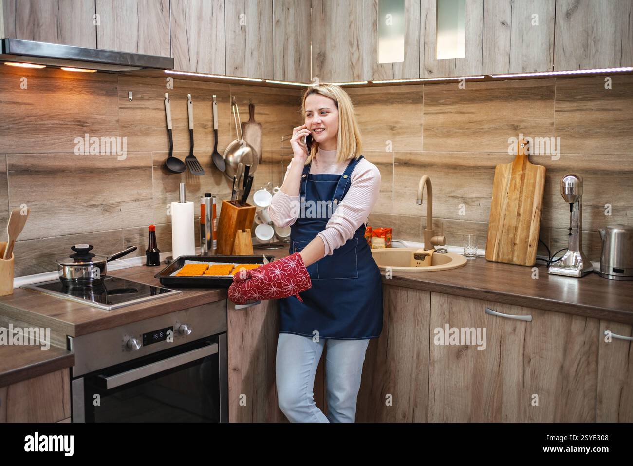Cooking in a modern kitchen while chatting on the phone with a friend ...