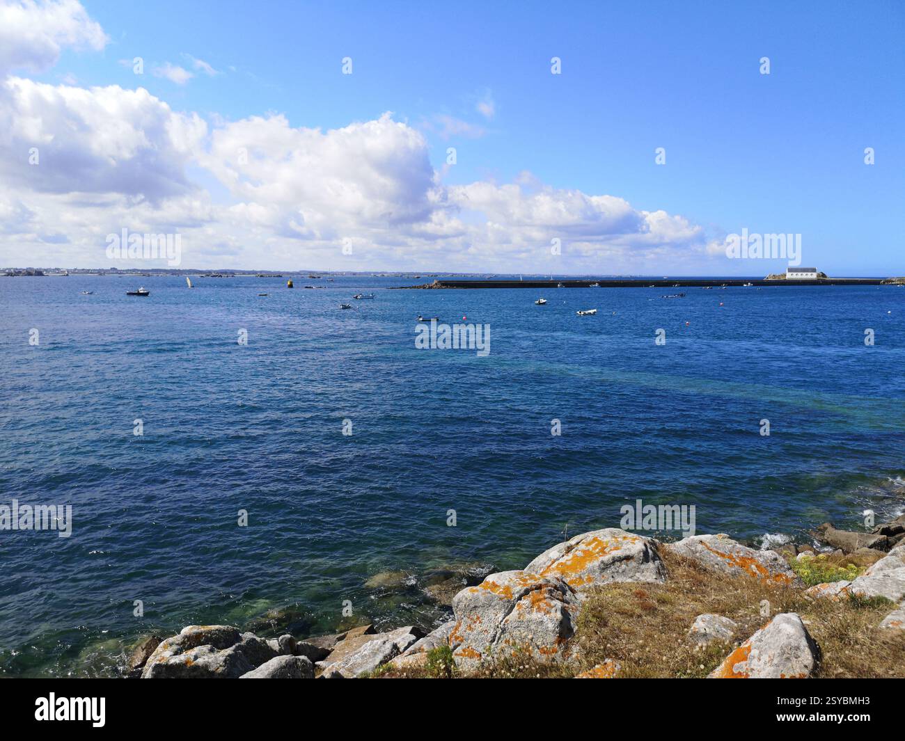 A scenic coastal view with a rocky shoreline and calm blue sea under a ...