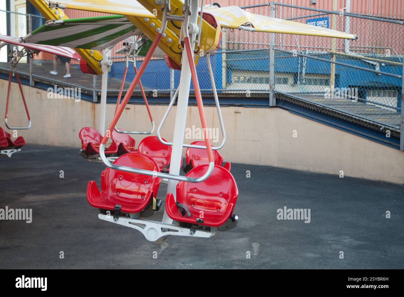 A stationary airplane-themed swing ride with bright red seats awaits ...