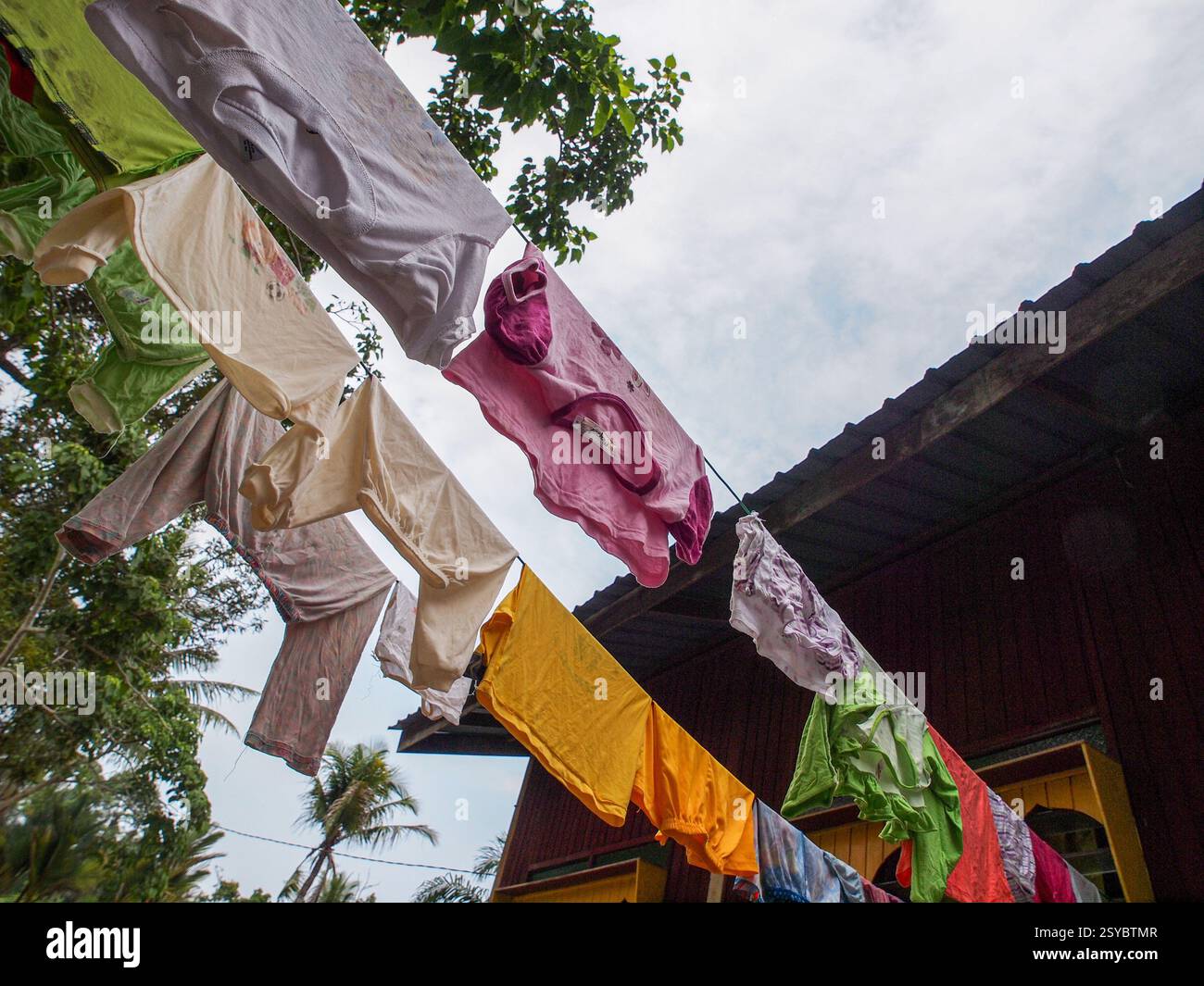 Kids children clothes and towels hanging on.a wire rope on a tree to ...