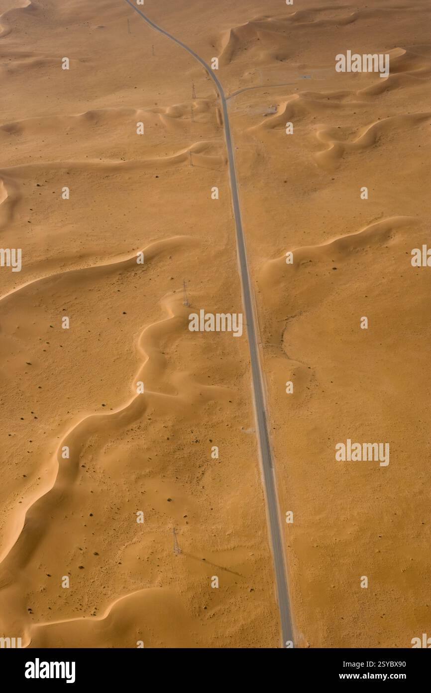 Aerial view of a straight road crossing sand dunes in the Sahara desert ...