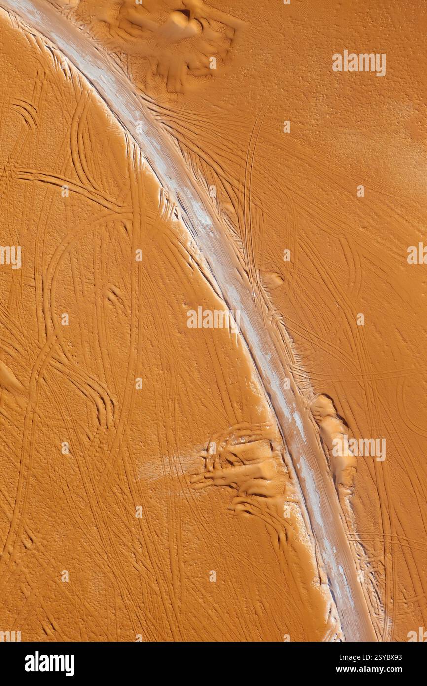 Aerial view of a straight road crossing sand dunes in the Sahara desert ...