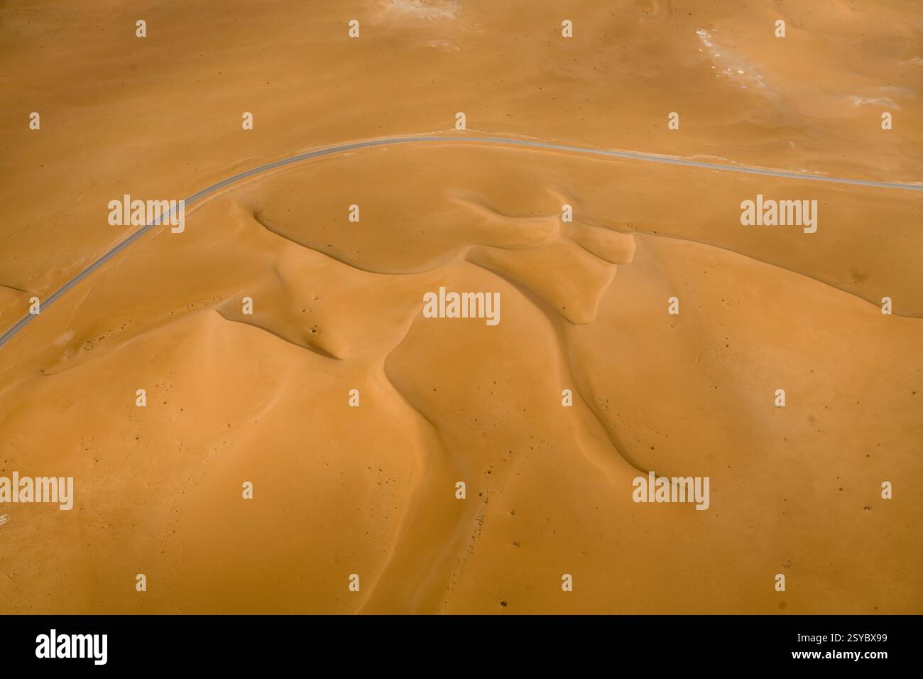 Aerial view of a straight road crossing sand dunes in the Sahara desert ...