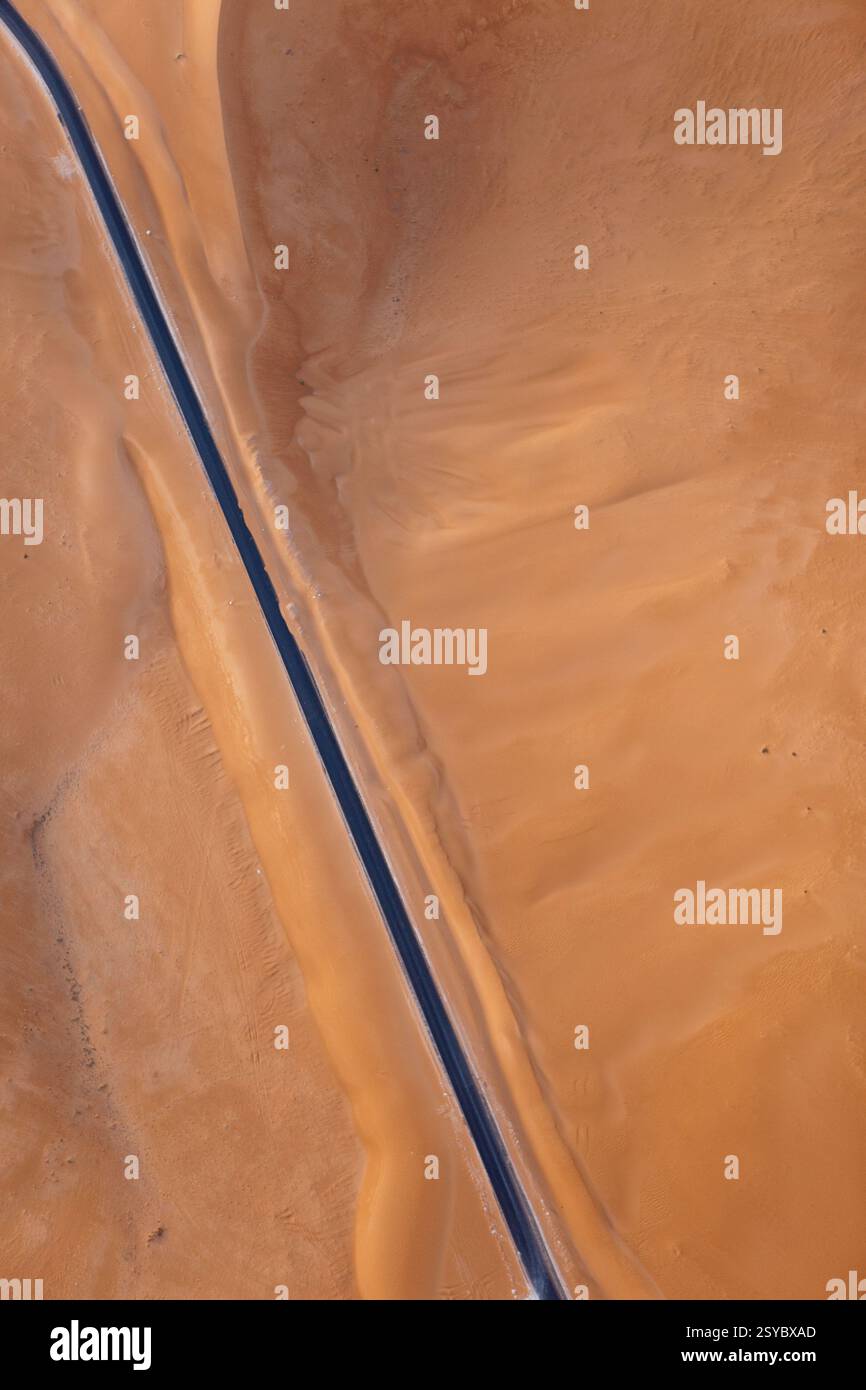 Aerial view of a straight road crossing sand dunes in the Sahara desert ...