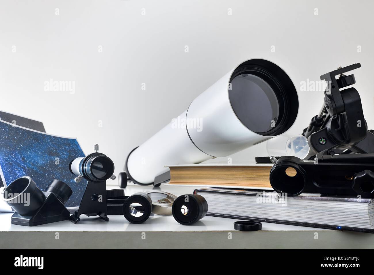 Parts of a telescope on white table with books and photos and white ...