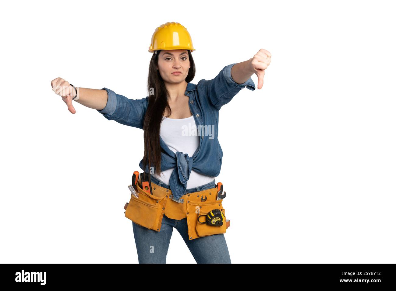 A female construction worker wearing a yellow safety helmet, denim shirt, and tool belt ...