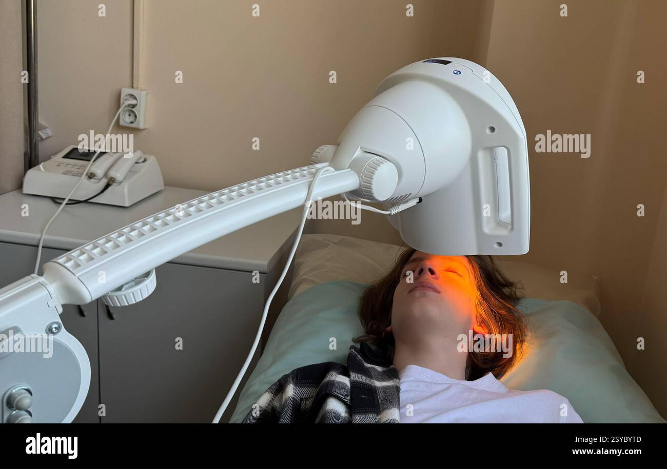 A teenager receiving infrared heat therapy to treat an eye condition ...