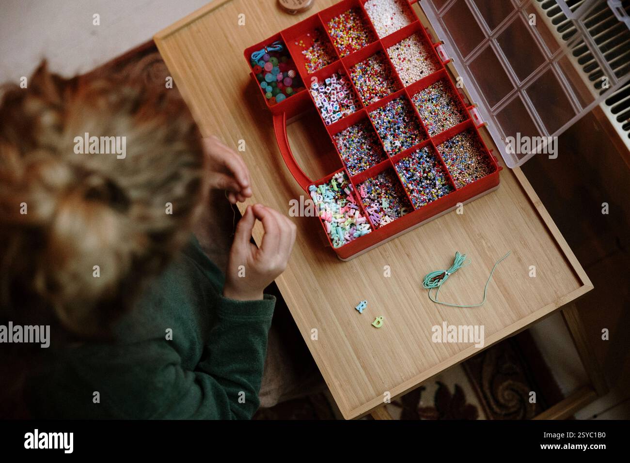 Child threading beads for a handmade craft project at home Stock Photo ...