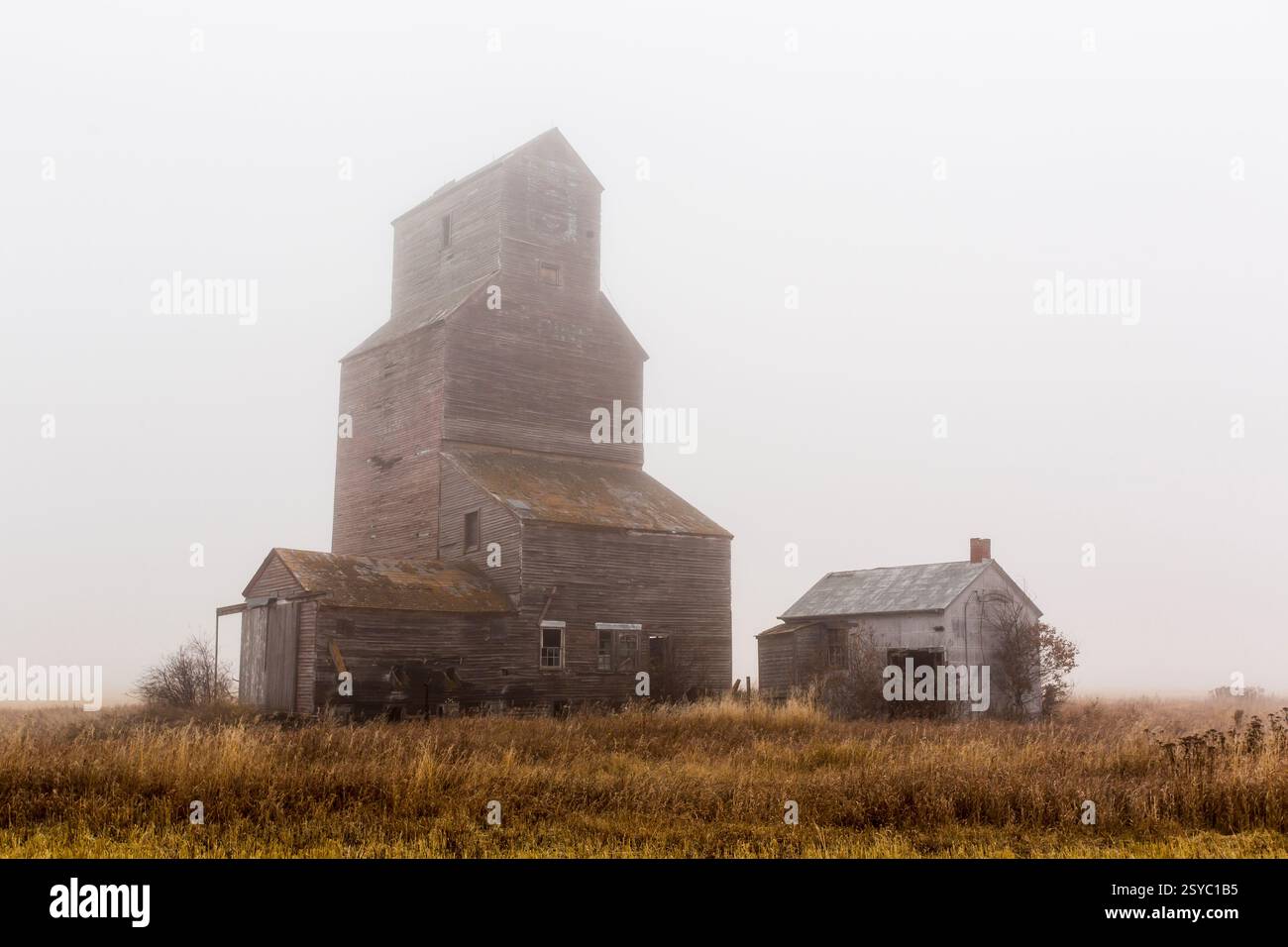 Small, old house and a large grain silo are situated in a vast, empty ...