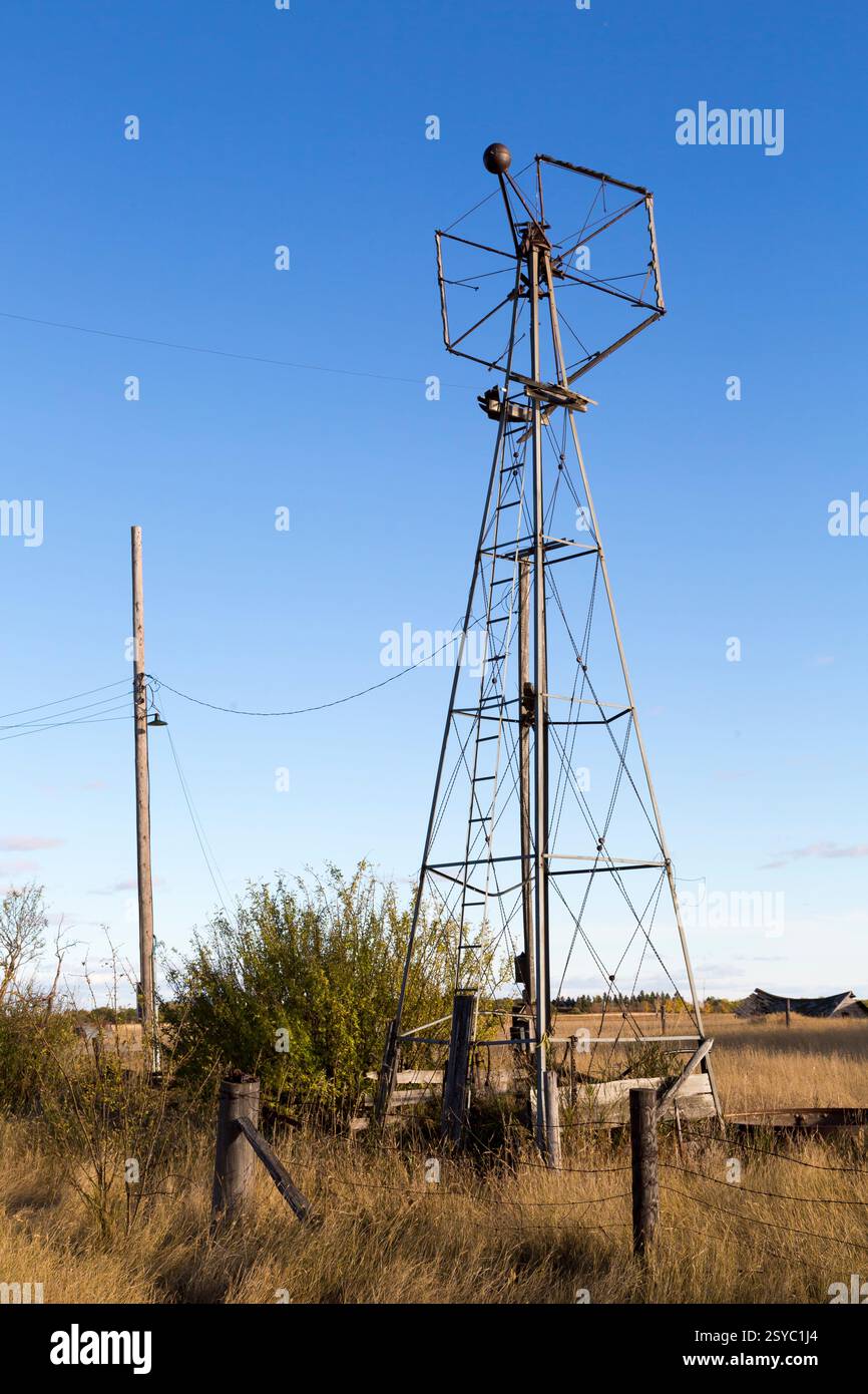 Windmill is standing in a field. The windmill is old and rusty. The sky is blue and clear Stock ...