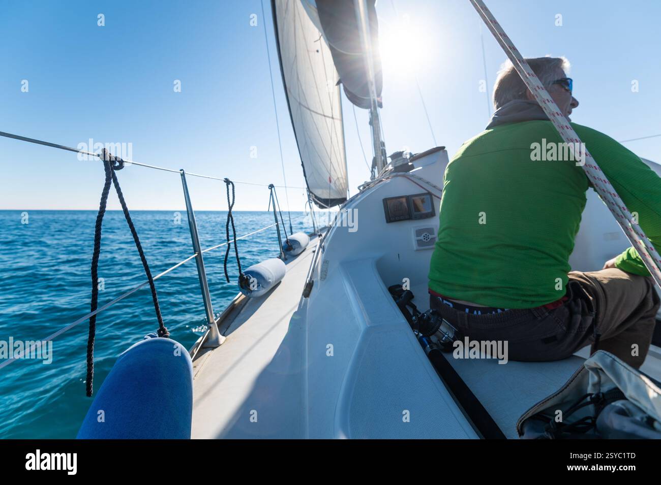 Sailor navigating sailboat in ocean on sunny day Stock Photo - Alamy
