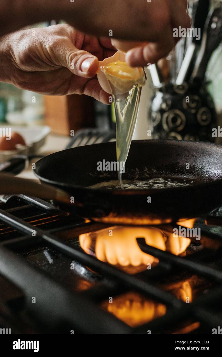 Close up of man cracking an egg into a hot pan on gas stove Stock Photo ...