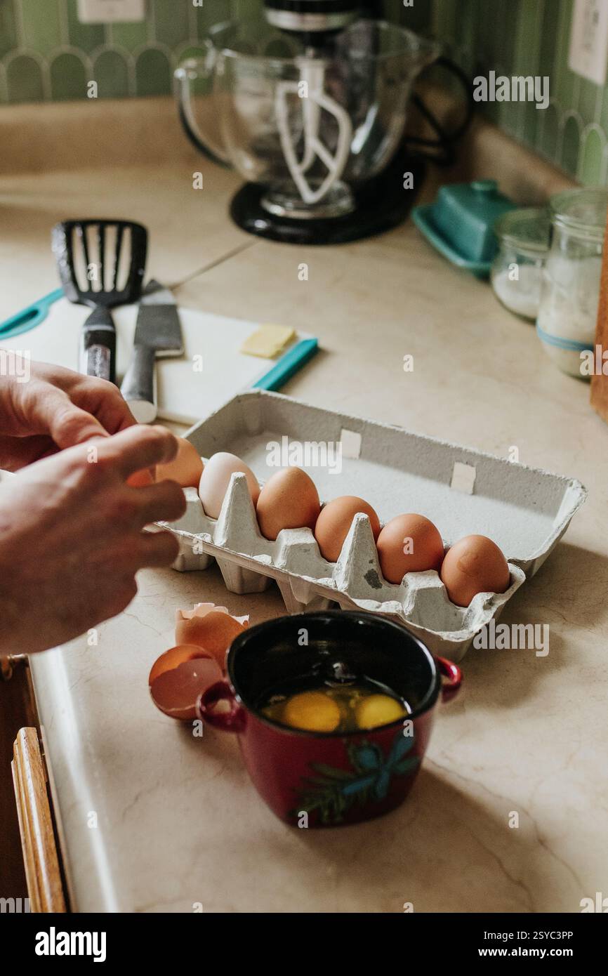 Man cracks fresh eggs into bowl sitting on counter to make breakfast ...