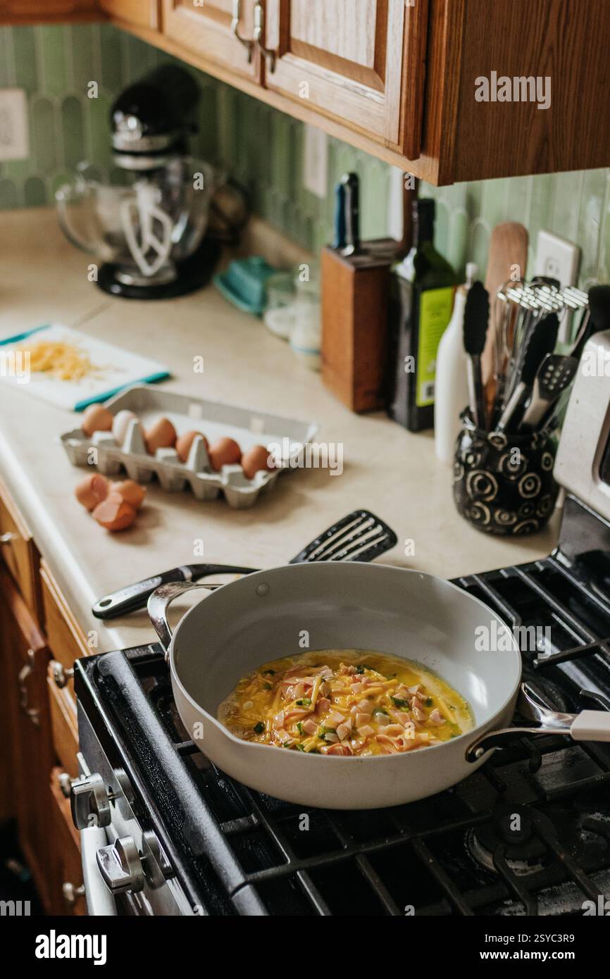 Egg, cheese, ham, and onion mixture cook on hot pan in kitchen Stock ...