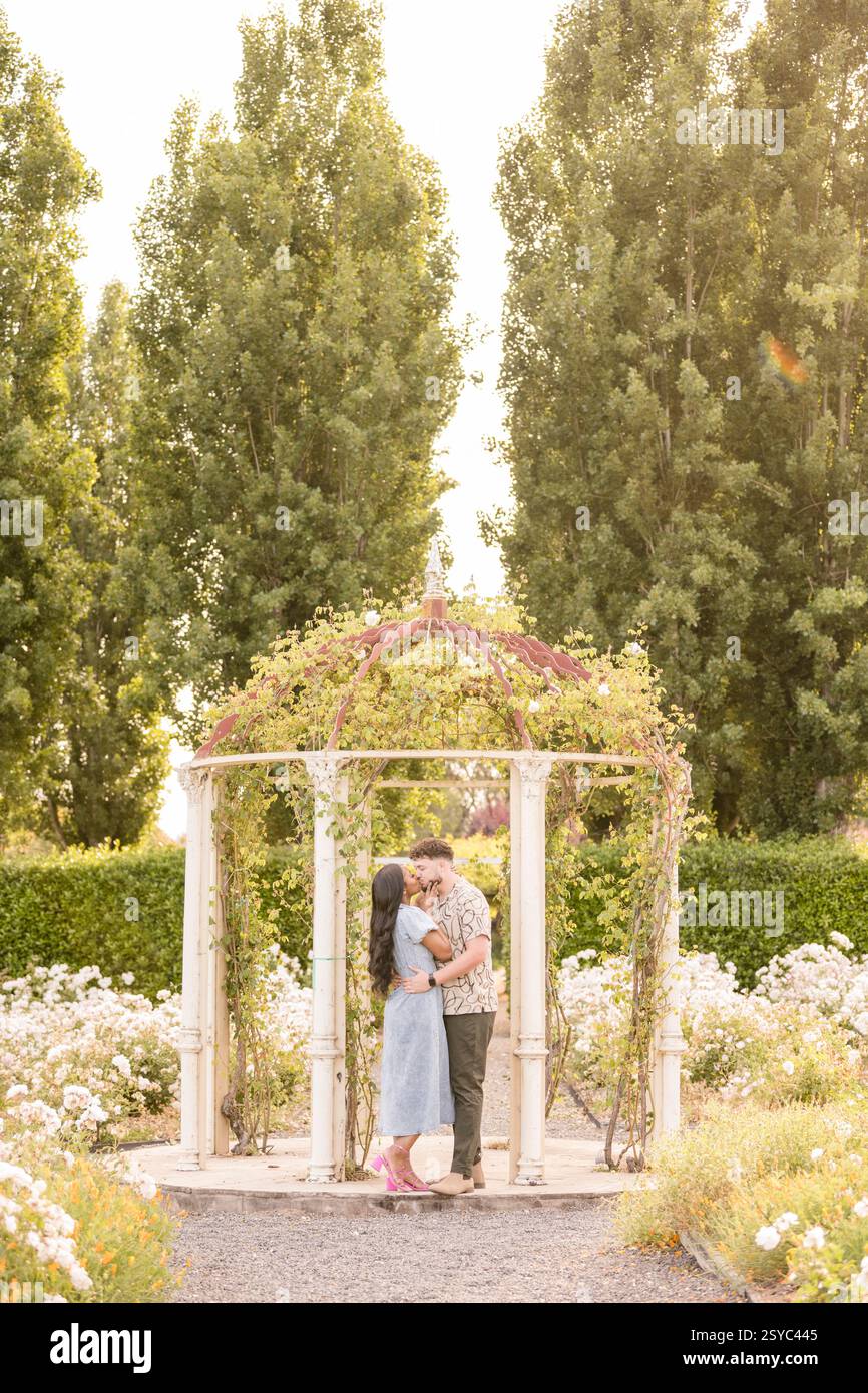 Romantic couple kissing under a vine-covered gazebo in a garden Stock ...