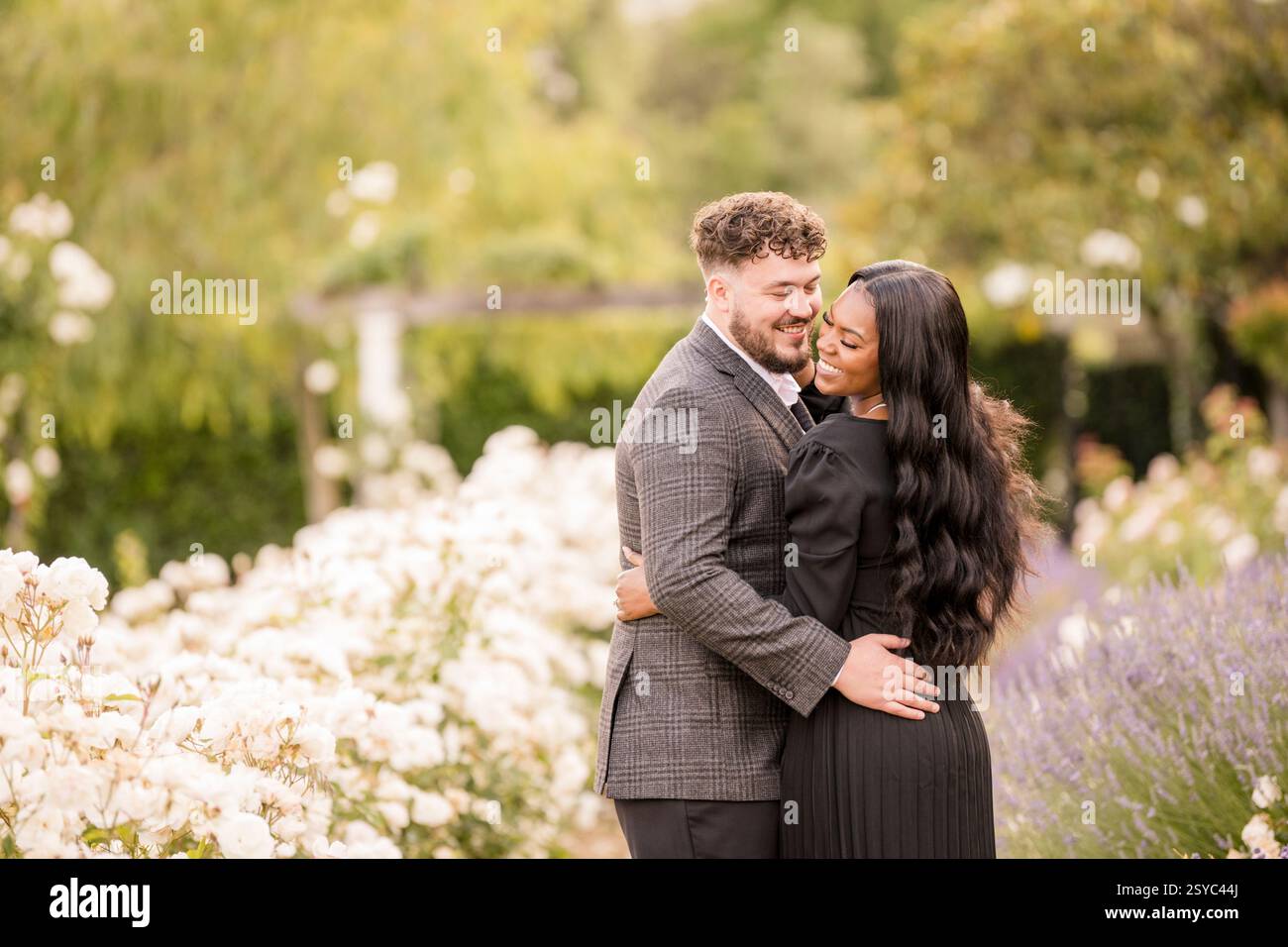 Couple sharing a loving embrace in a flower garden Stock Photo - Alamy