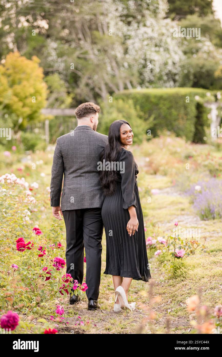 Smiling woman glancing back while walking with partner Stock Photo - Alamy
