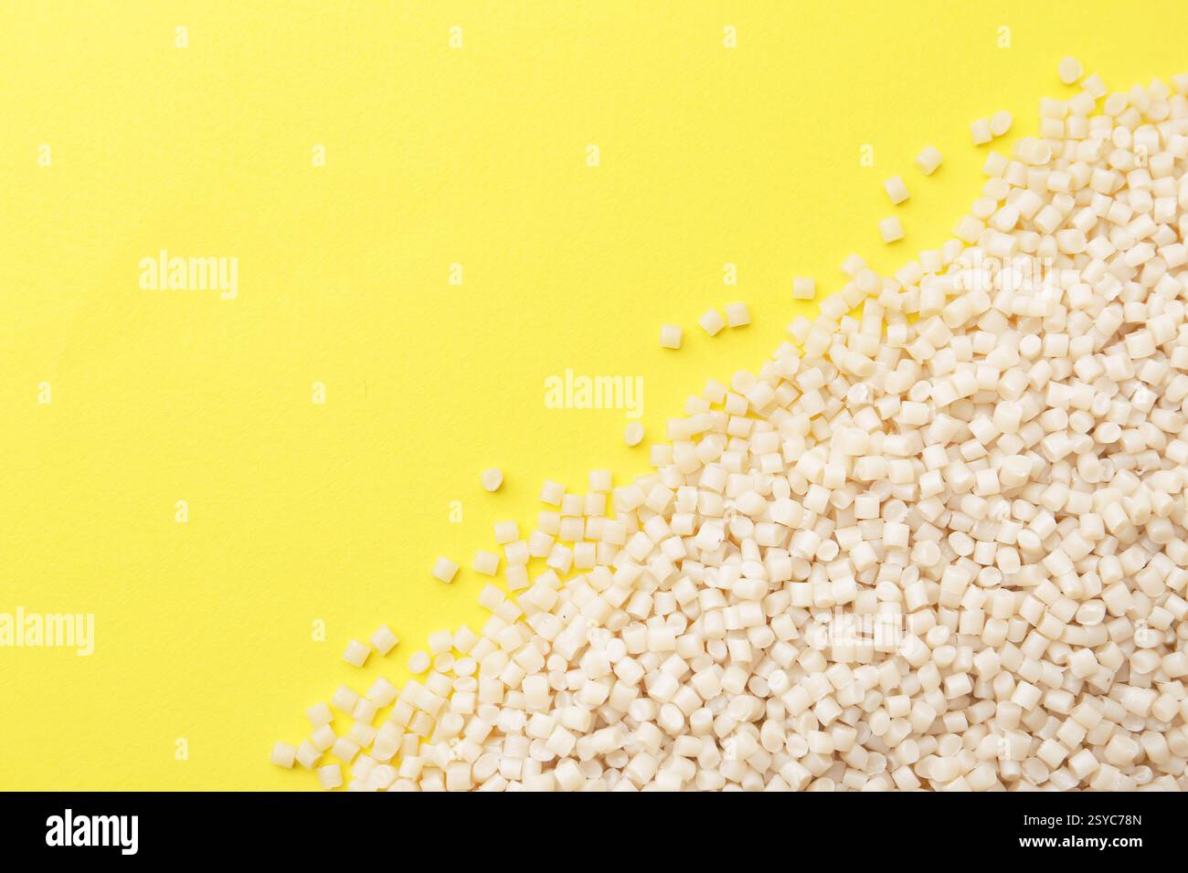 Pile of plastic granules on yellow background, top view. Space for text ...