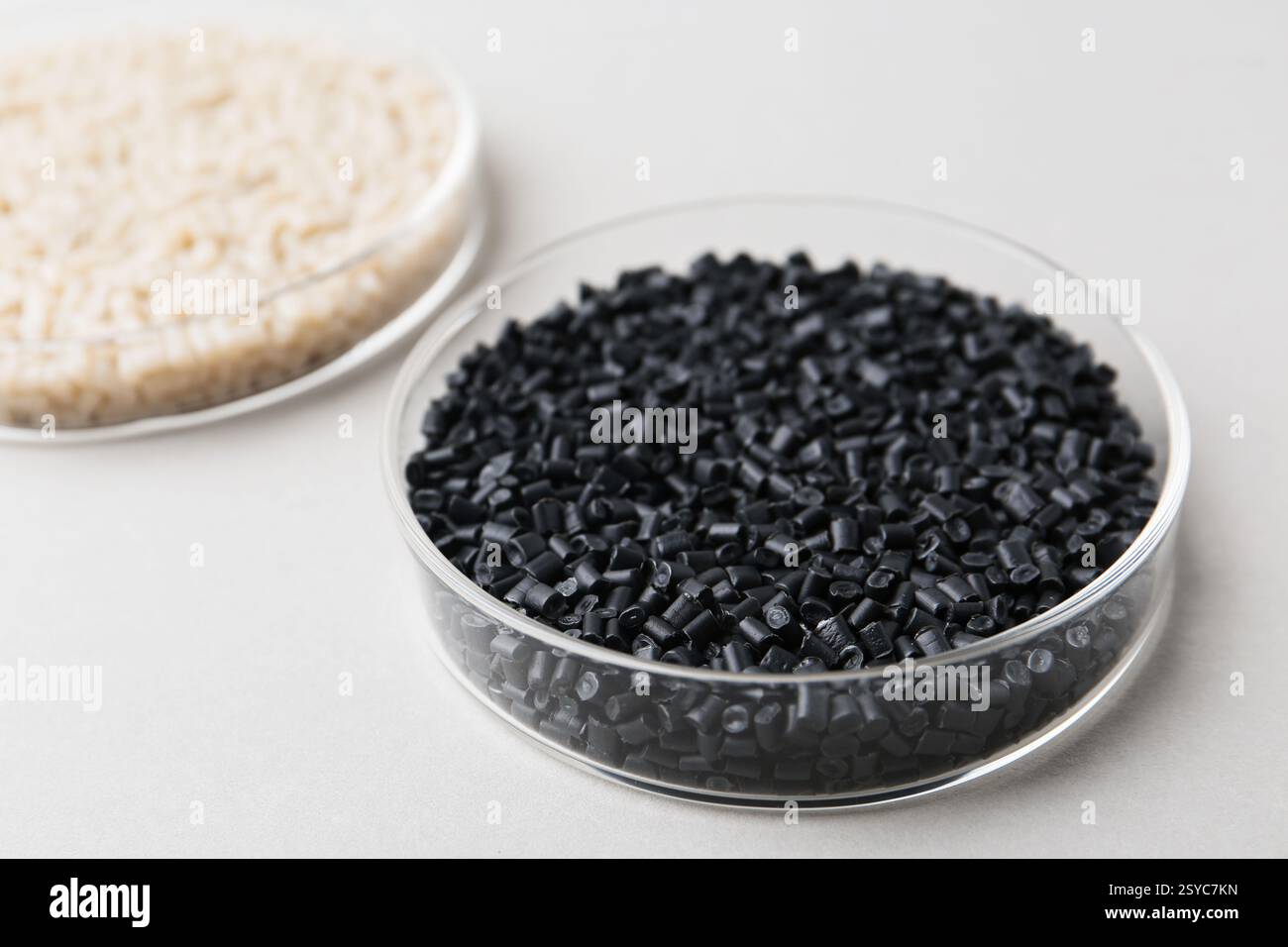 Colorful plastic granules in petri dishes on gray background, closeup ...