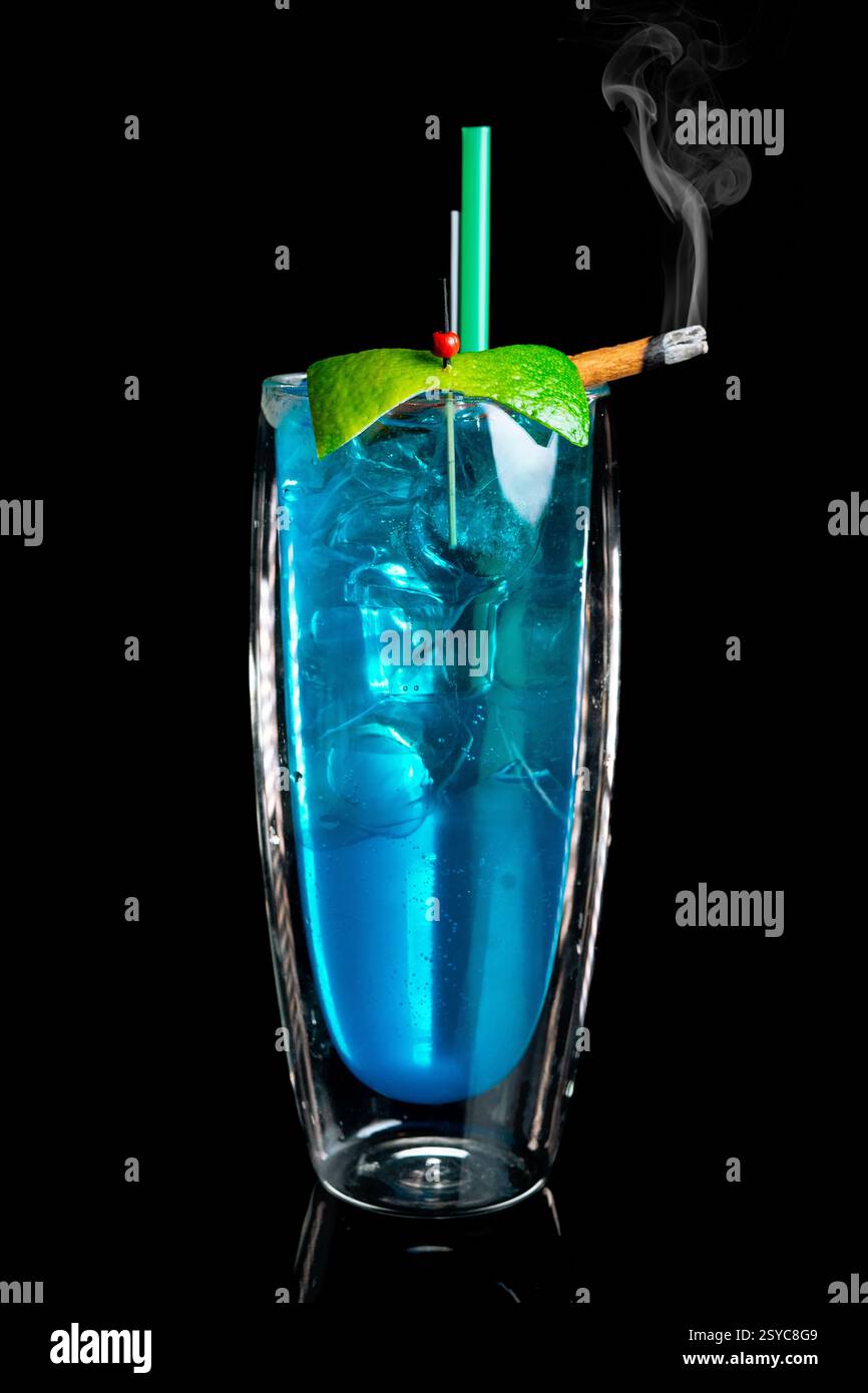 Masculine cocktail with Blue Curaçao, ice, a smoking cigar, and a lime ...