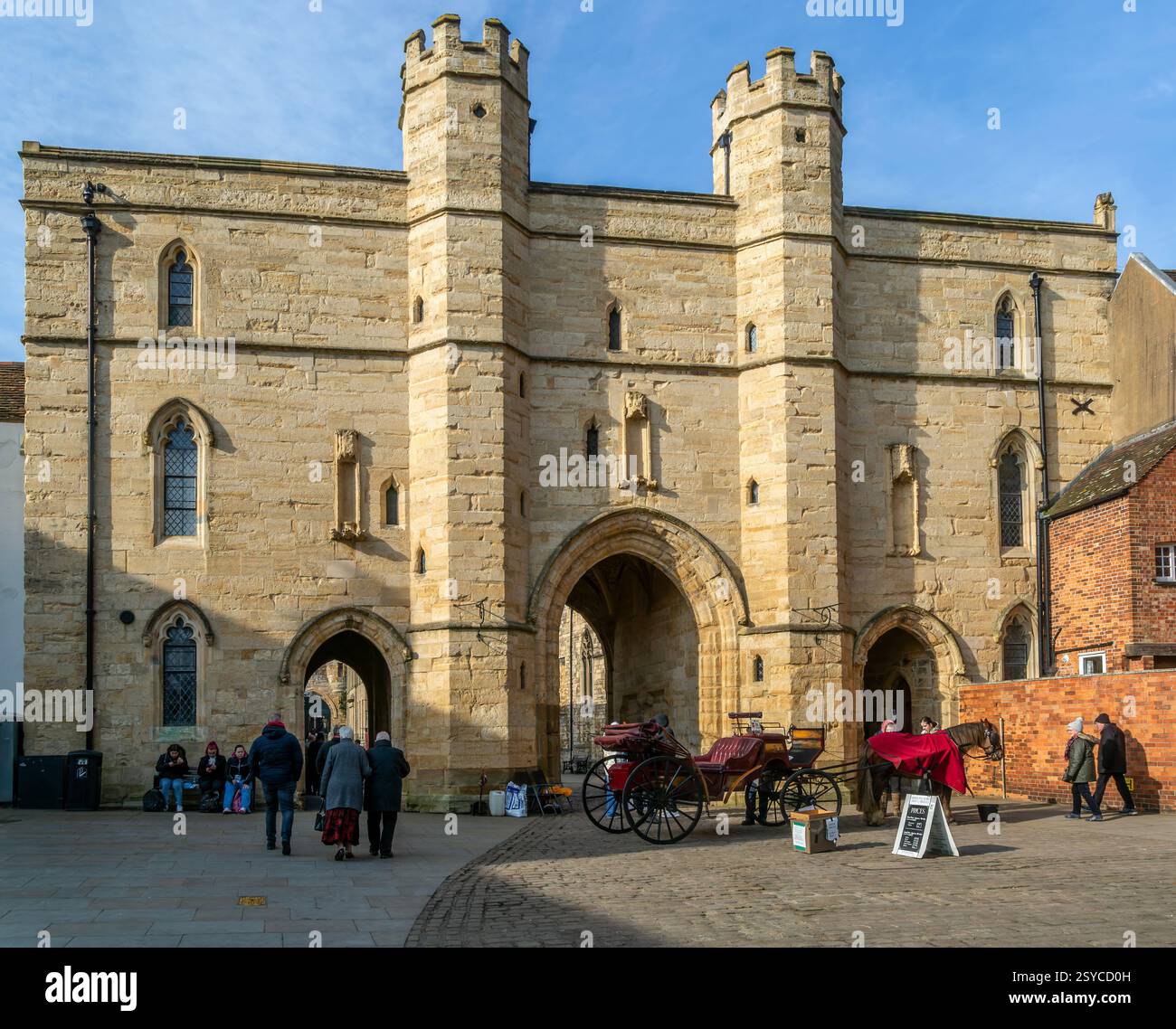 Sun shining on Exchequer Gate with horse carriage rides, Minster Yard ...