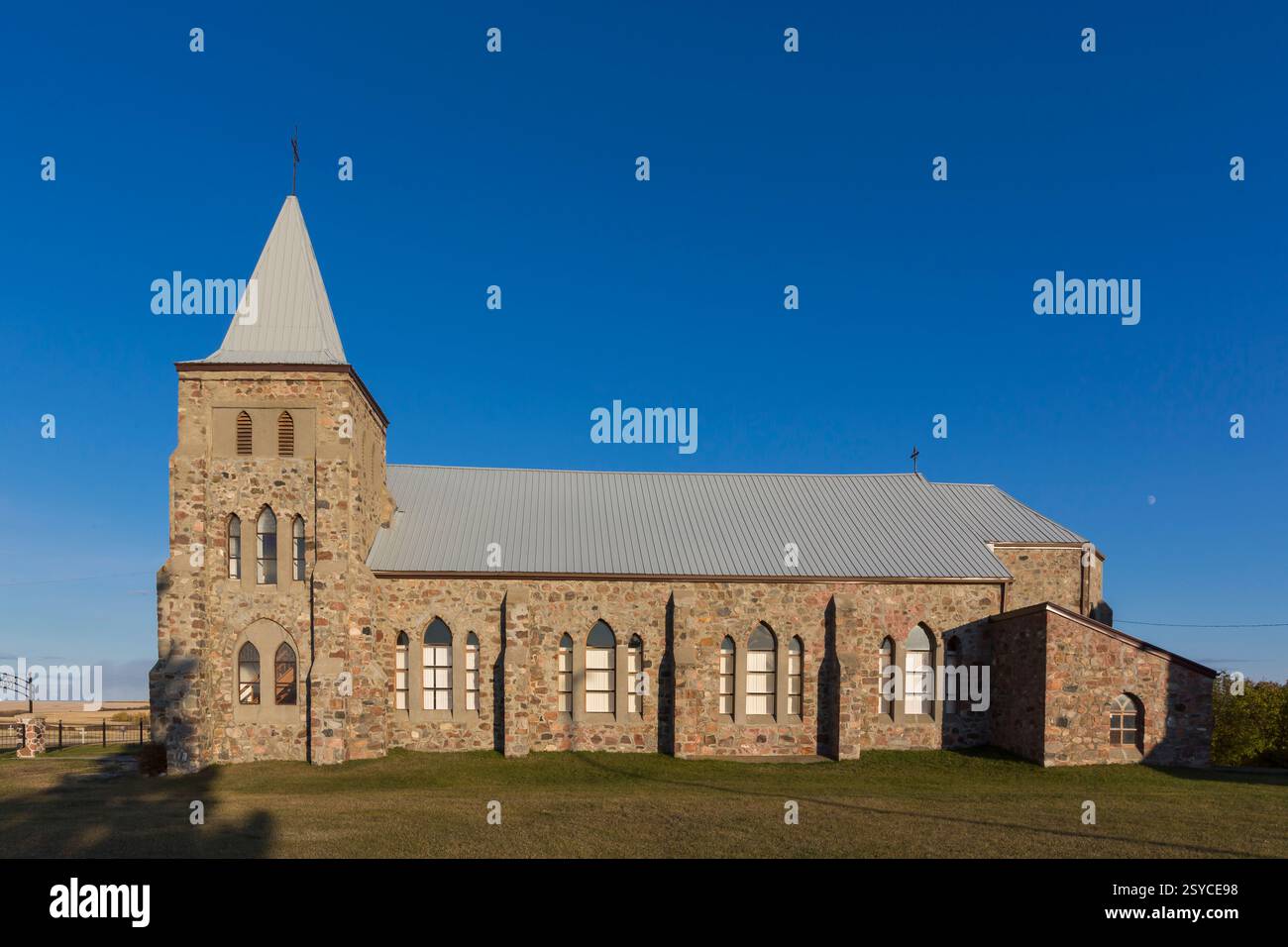 Large stone building with a steeple and a cross on top. The building is ...