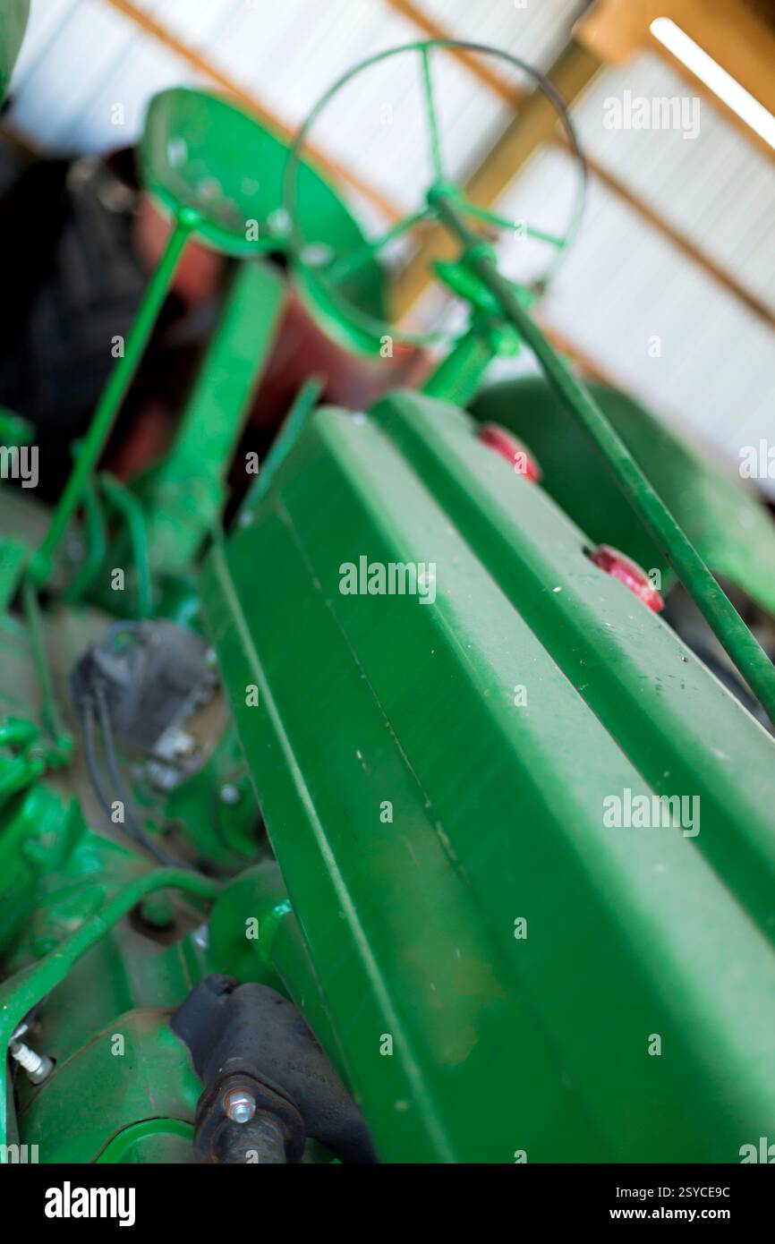 Green tractor engine with a black tire. The engine is in a barn Stock ...