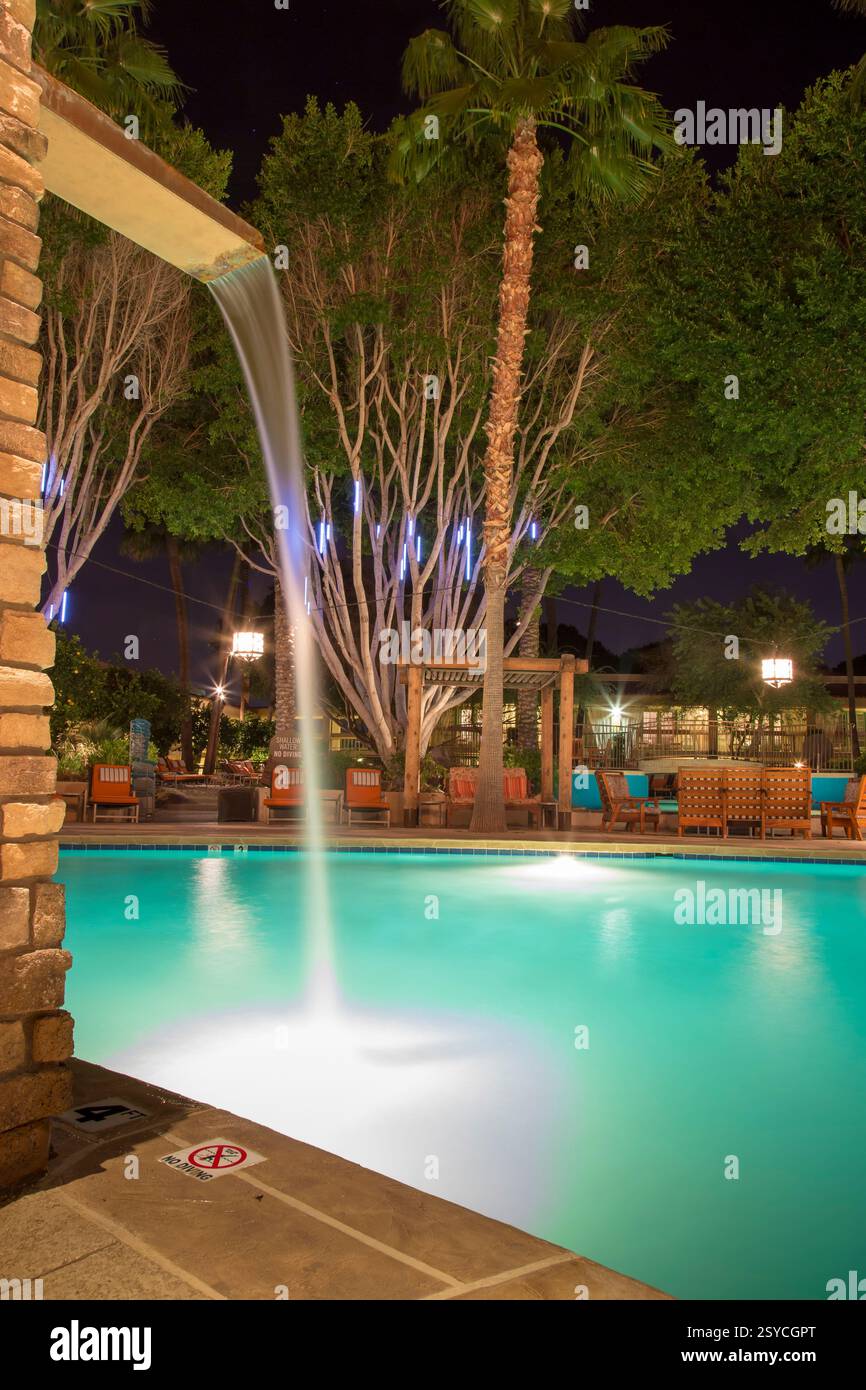Pool with a waterfall and a sign that says no diving. The pool is lit ...