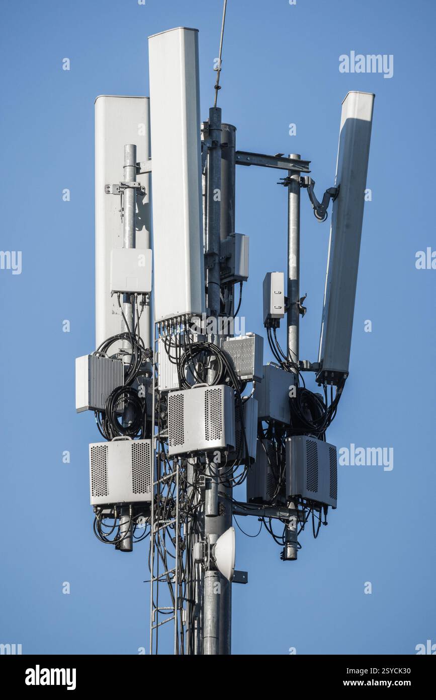 A telecommunications cell tower featuring multiple antennas and equipment, photographed against ...