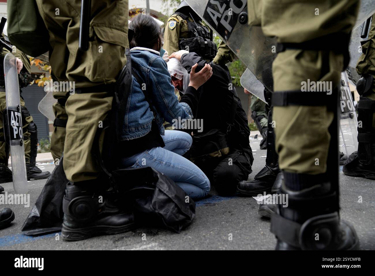 An injured protestor touches his head surrounded by the riot police ...