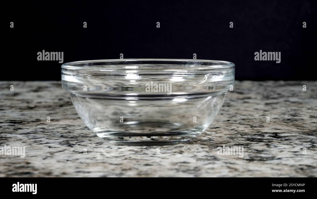 Clear glass bowl on granite countertop with dark background showing ...