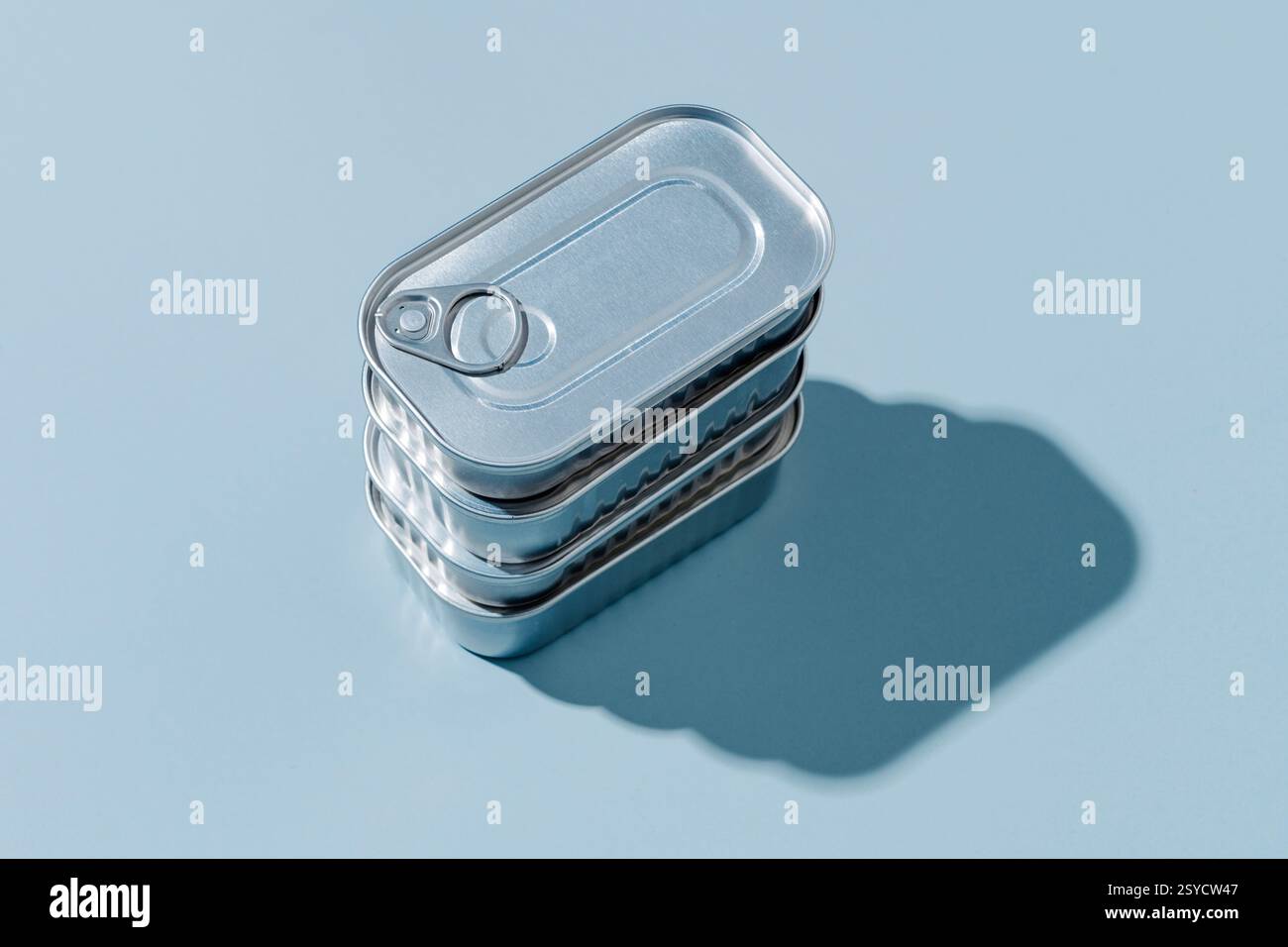 a stack of some unopened cans of canned food, on a light blue ...