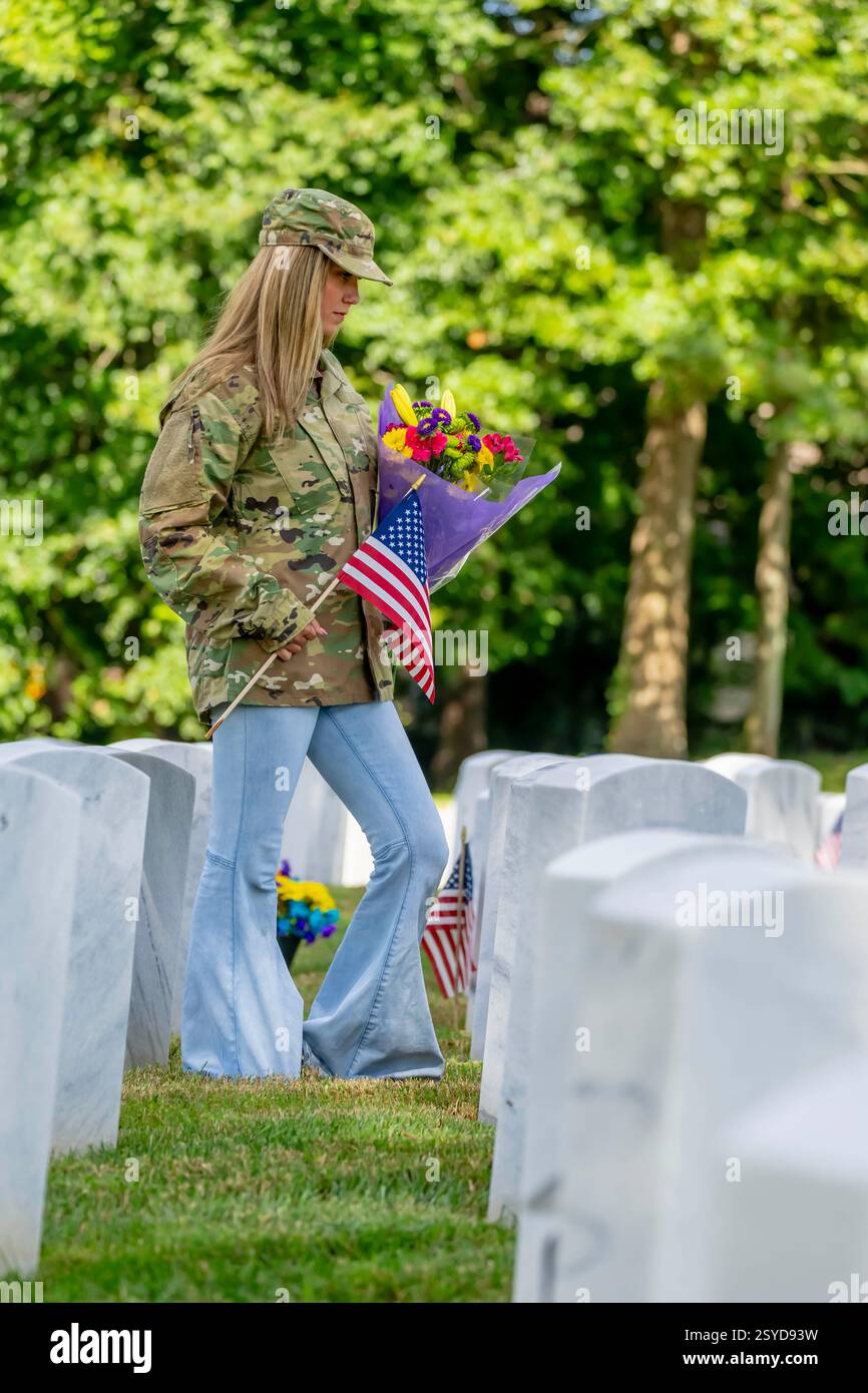 A young bride kneels at a military cemetery amid uniform rows of graves ...