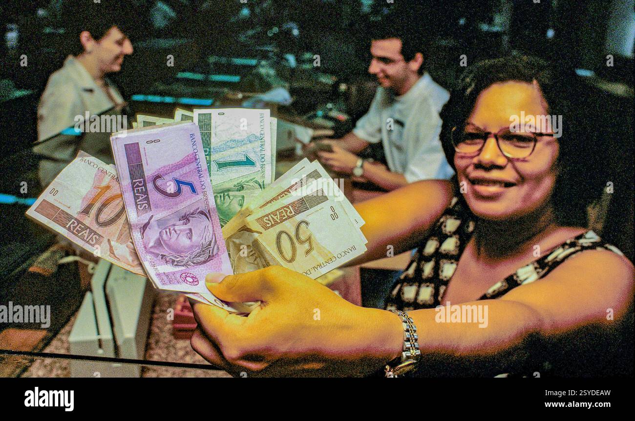 Brazil, Sao Paulo, a cashier in a bank shows Real notes, the currency ...