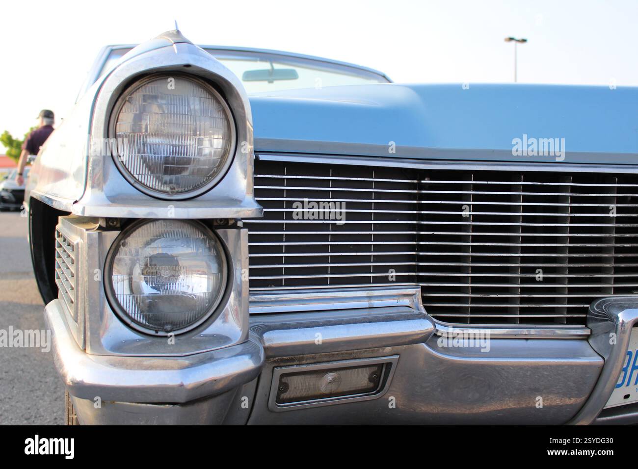 A classic light blue Cadillac convertible parked at a lively car show ...