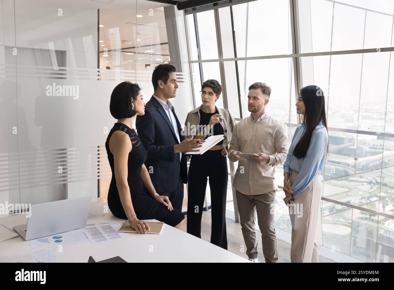 Focused business team stand around mature male leader explaining ...