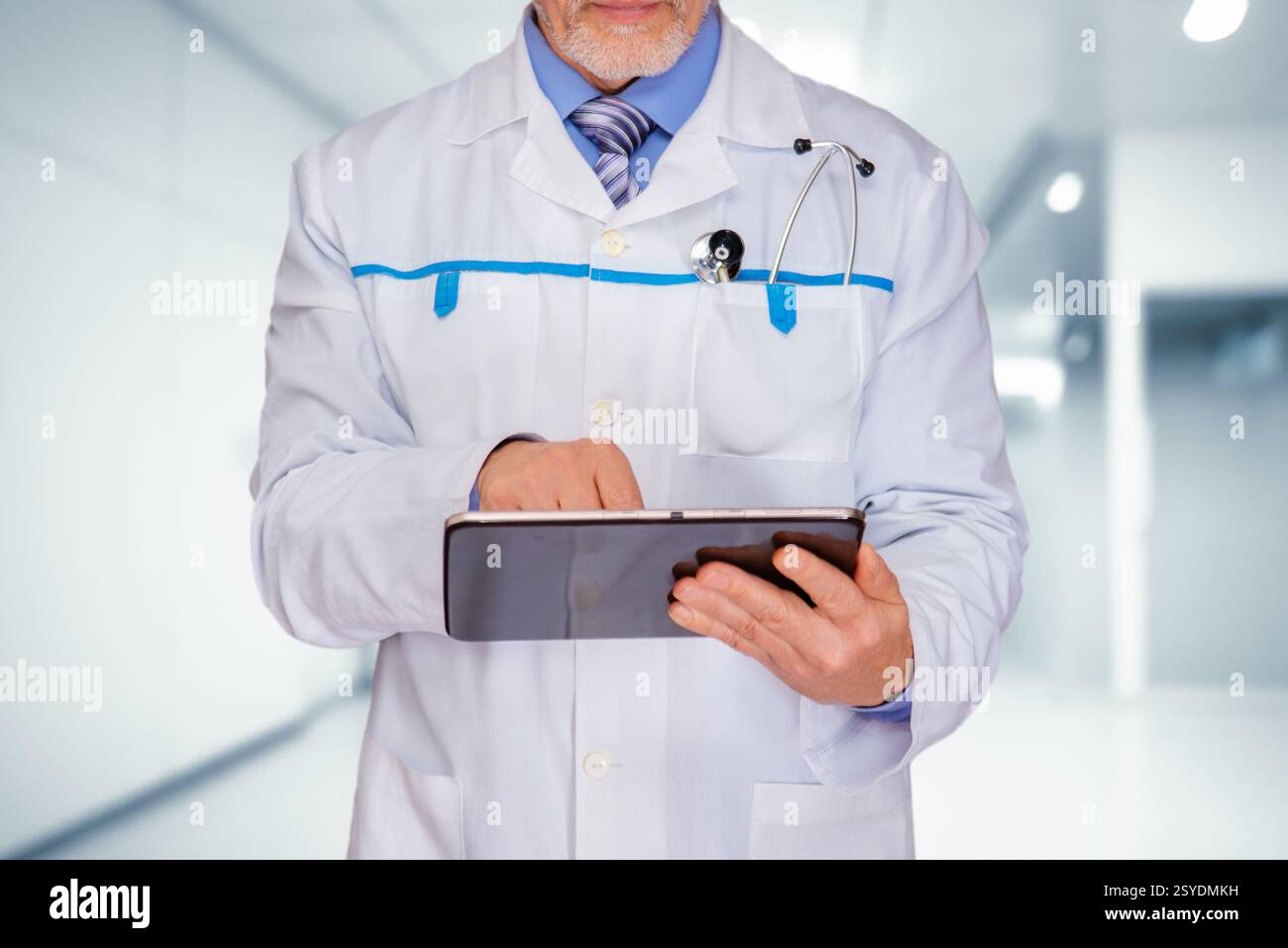 A healthcare worker engages with a digital tablet while wearing a white ...