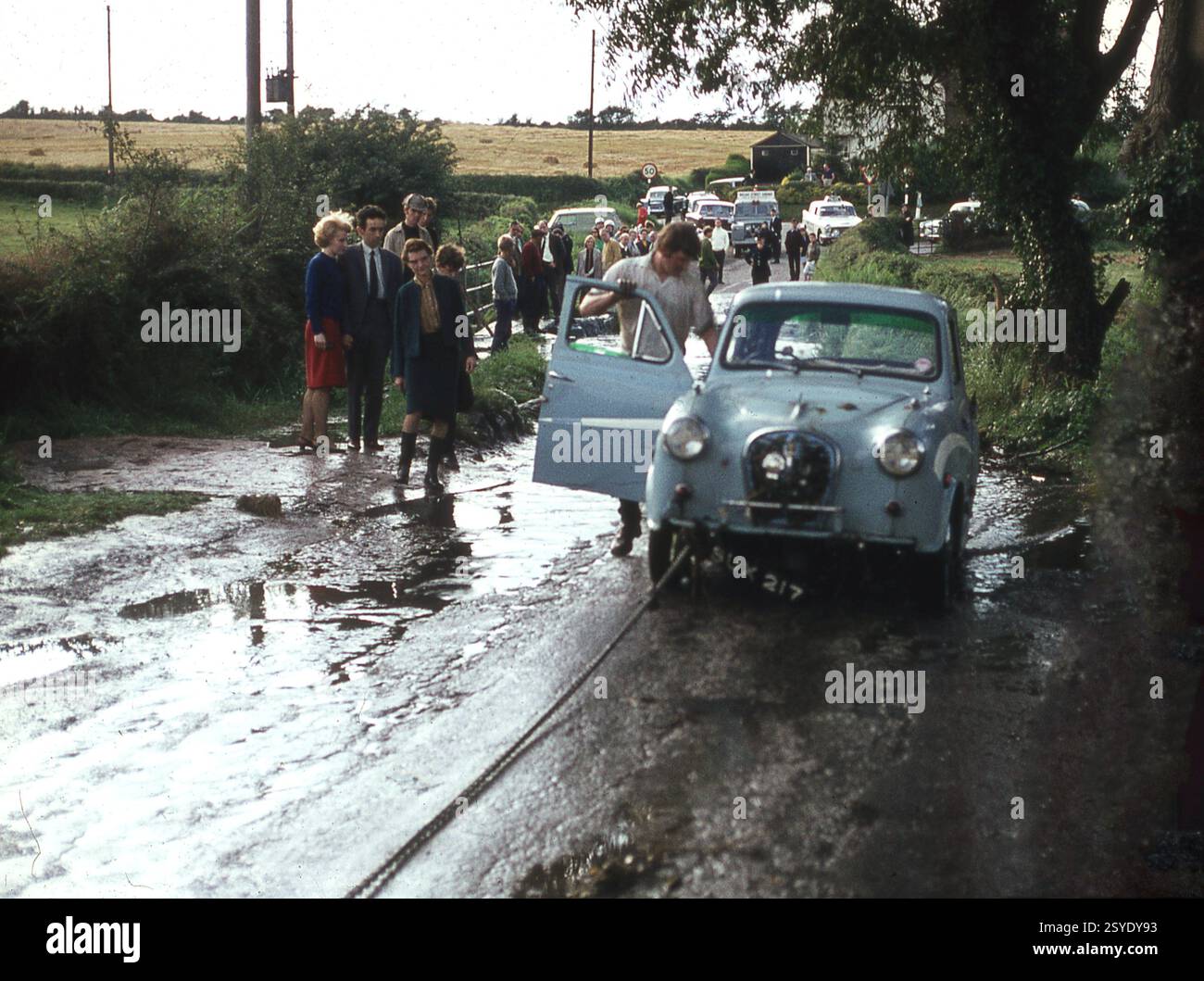 1970s, people watching a small Austin car being towed on a small ...