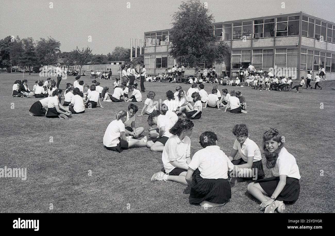 1989, school sports day, small groups of schoolgirls in PE kit sitting ...