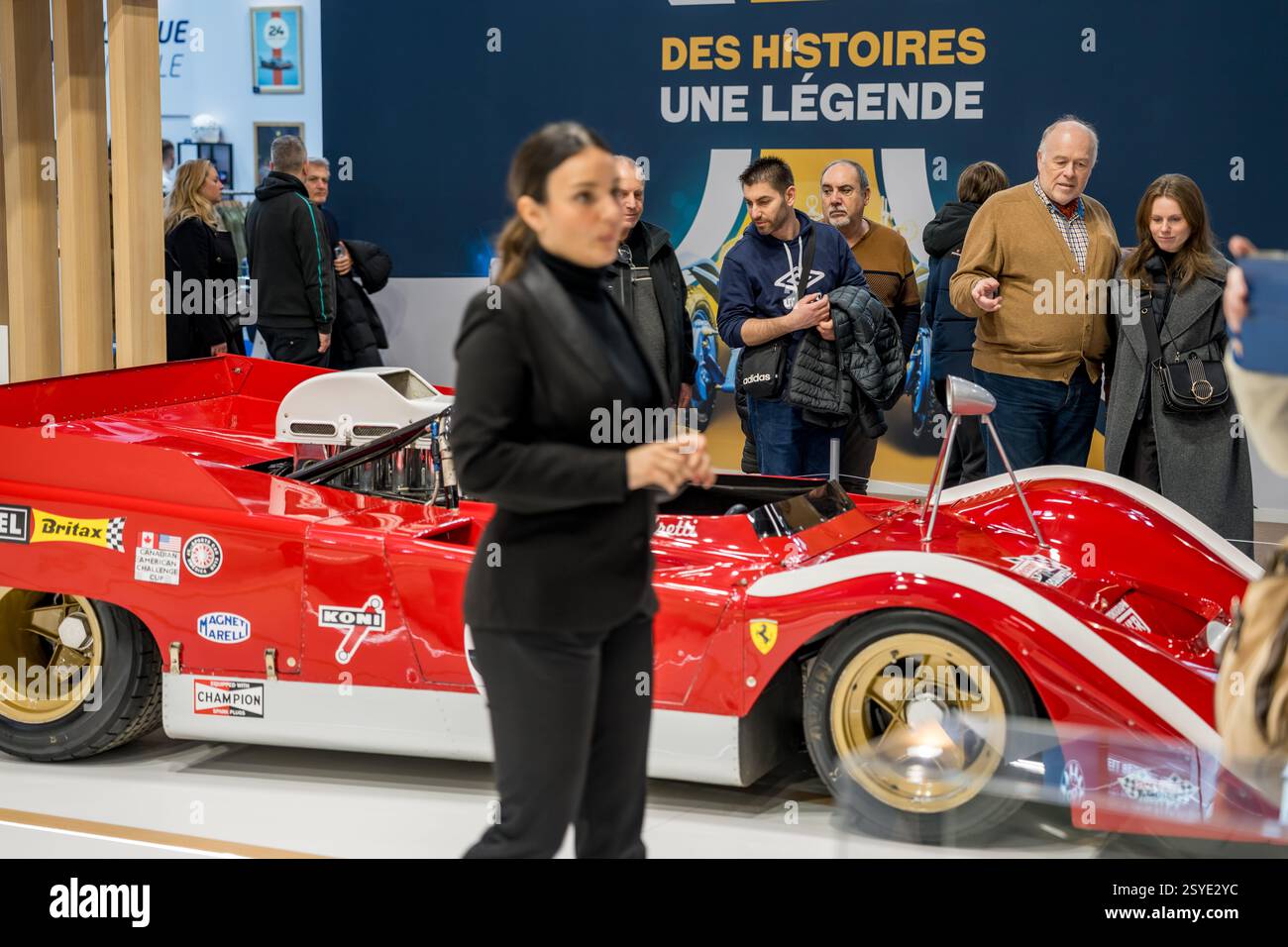 Enthusiasts admire a classic racing car at an auto show while a ...