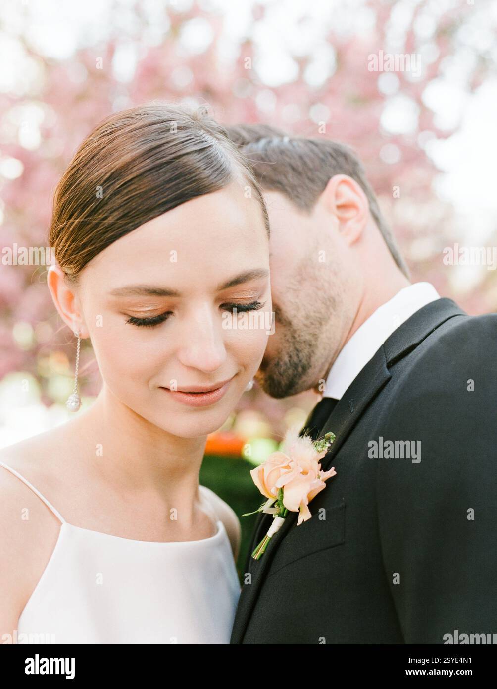 A couple shares a tender moment at a wedding, with delicate blossoms ...