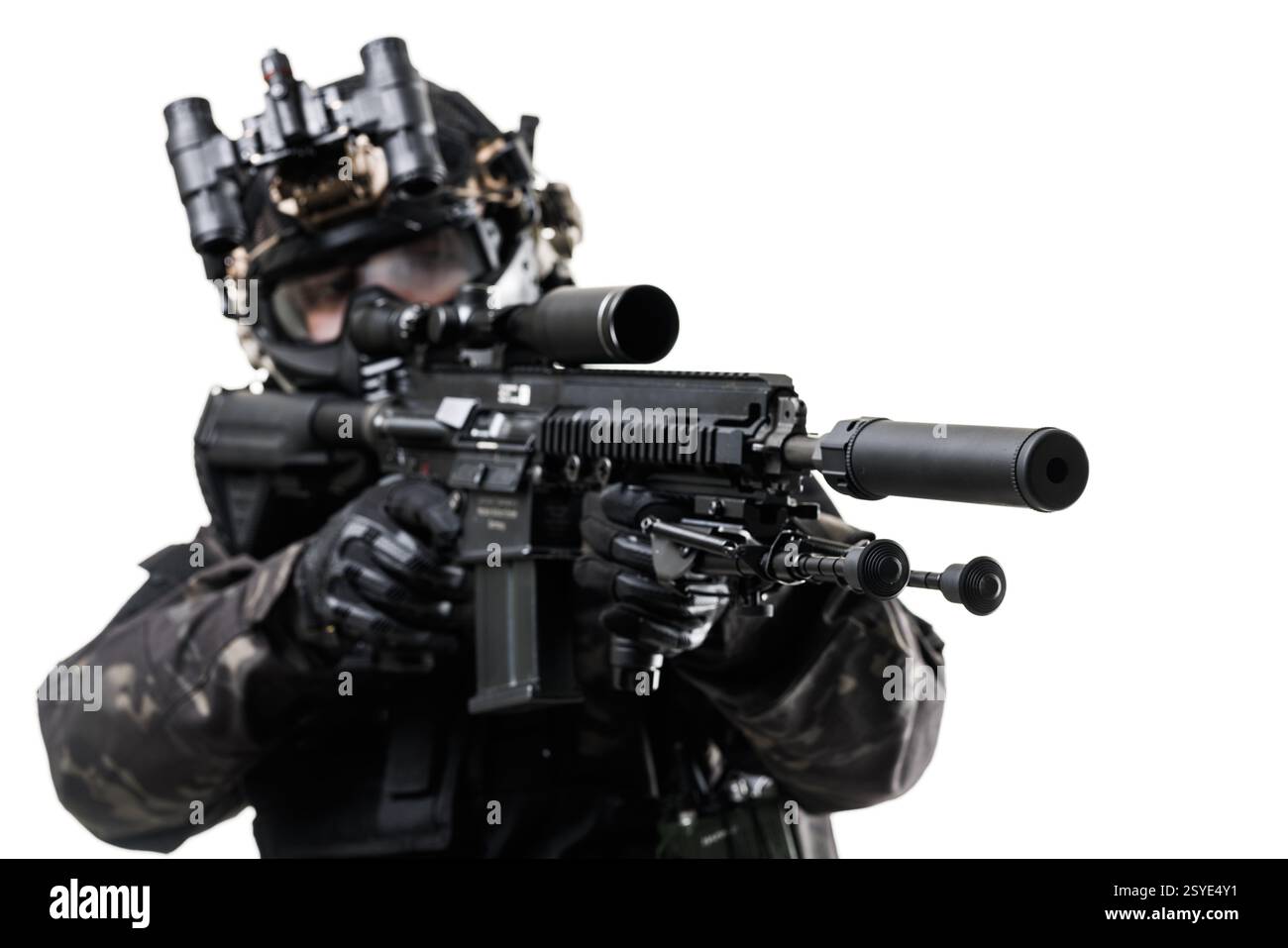 Special forces operative in tactical gear and weaponry aiming in studio ...
