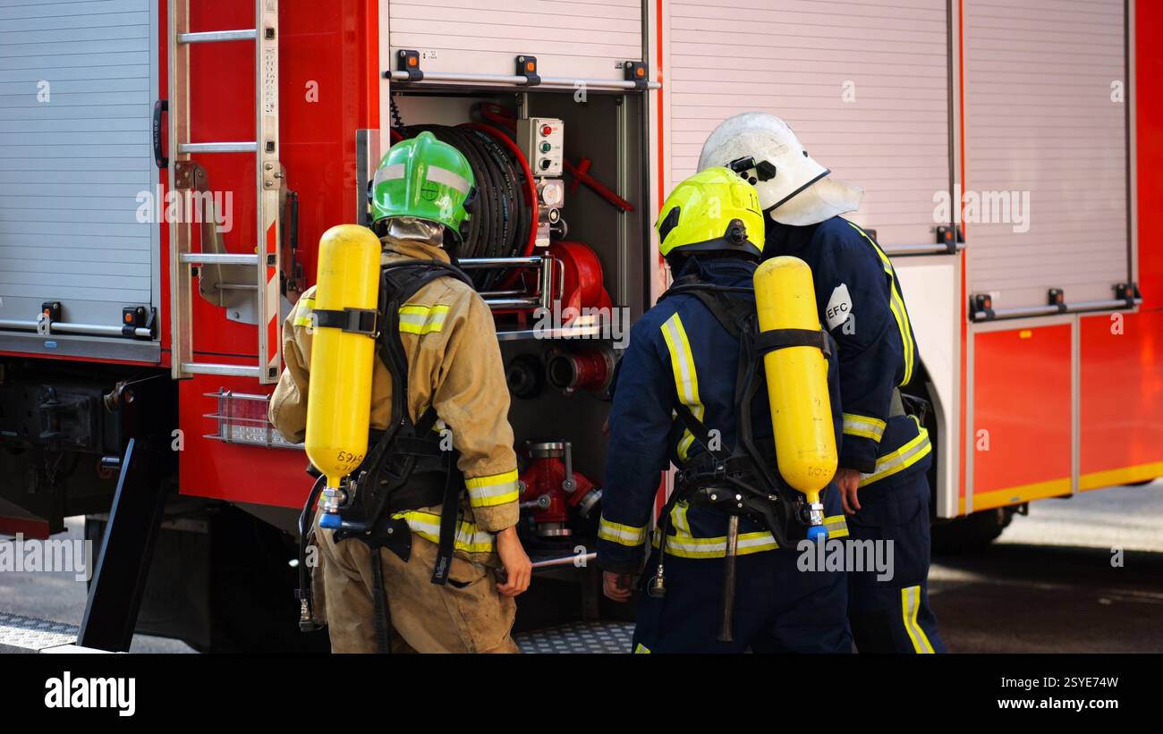 Young firemen prepare to extinguishing fire near big truck. Male ...