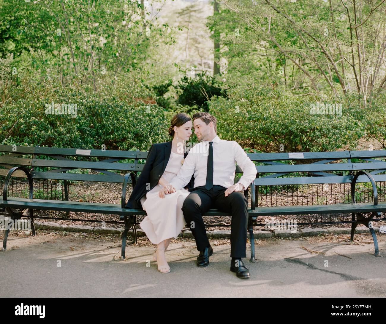 A couple enjoys a quiet moment together on a park bench in a lush ...