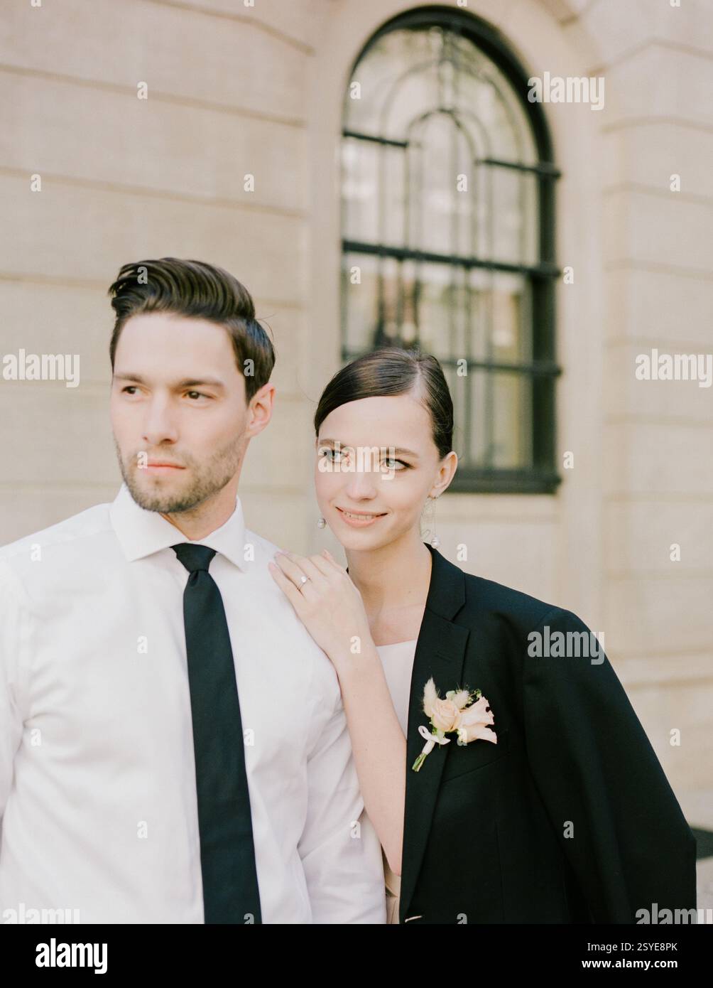 A couple stands close, their elegant outfits and joyful smiles shining ...