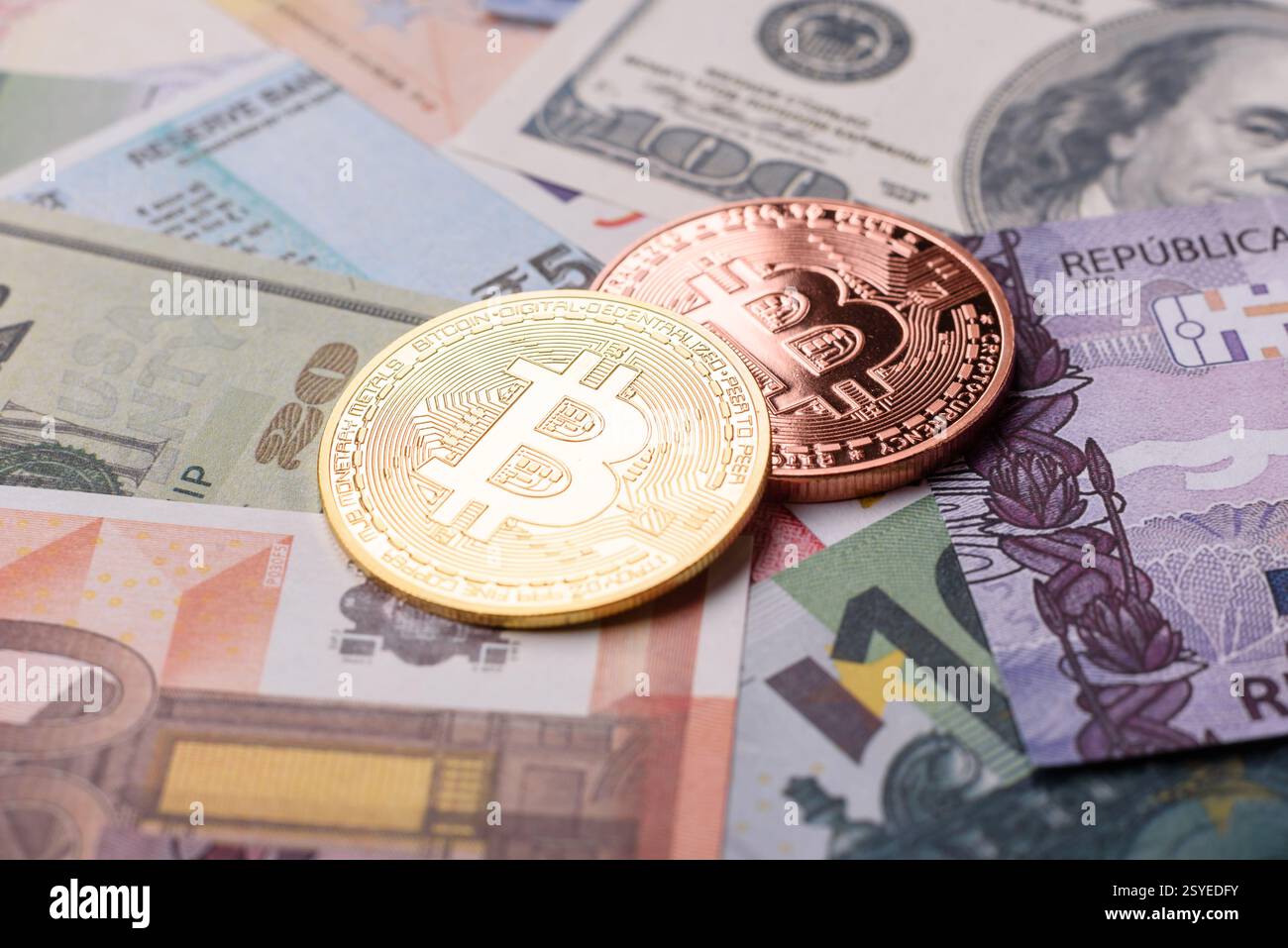 Round metal bitcoin on a background of paper banknotes of different ...